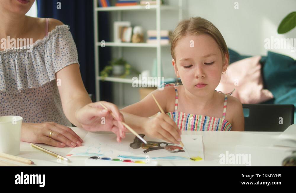 Young mother teaching her daughter to draw. Lovely babysitter drawing ...