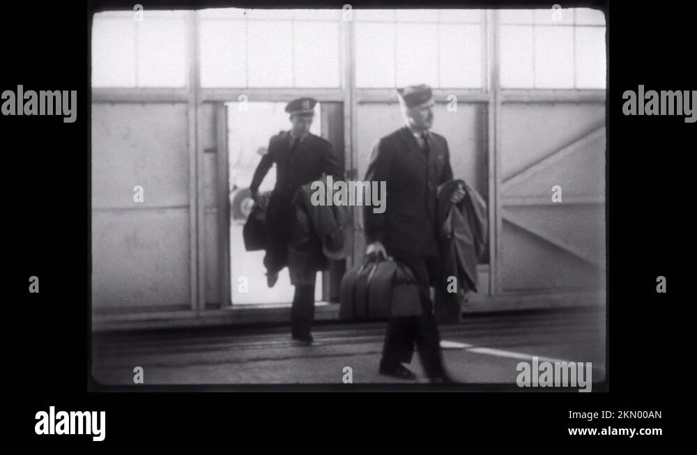 1950s: Military personnel, officers, stand in rows in hangar, waiting ...