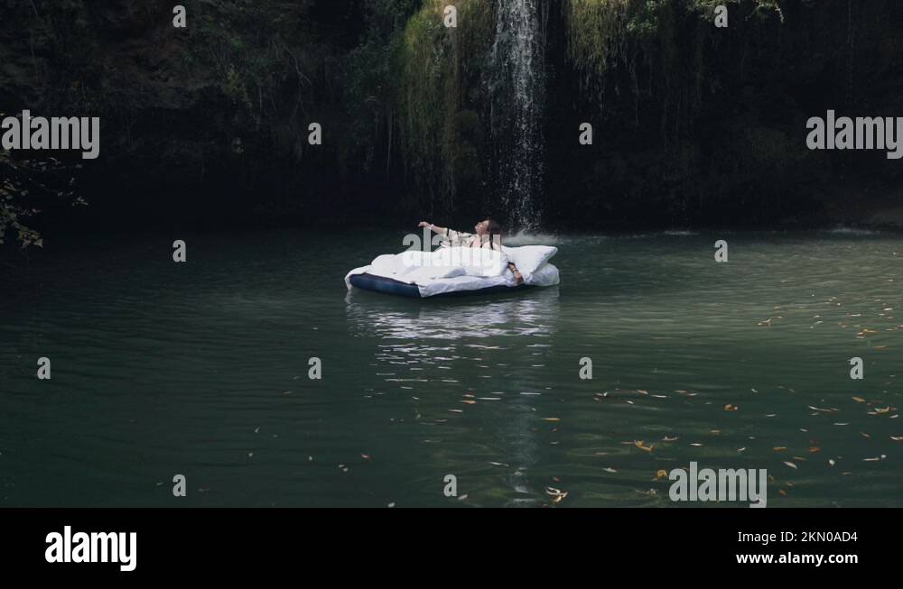 Sleeping girl floating on bed in water surrounded by wildlife and ...