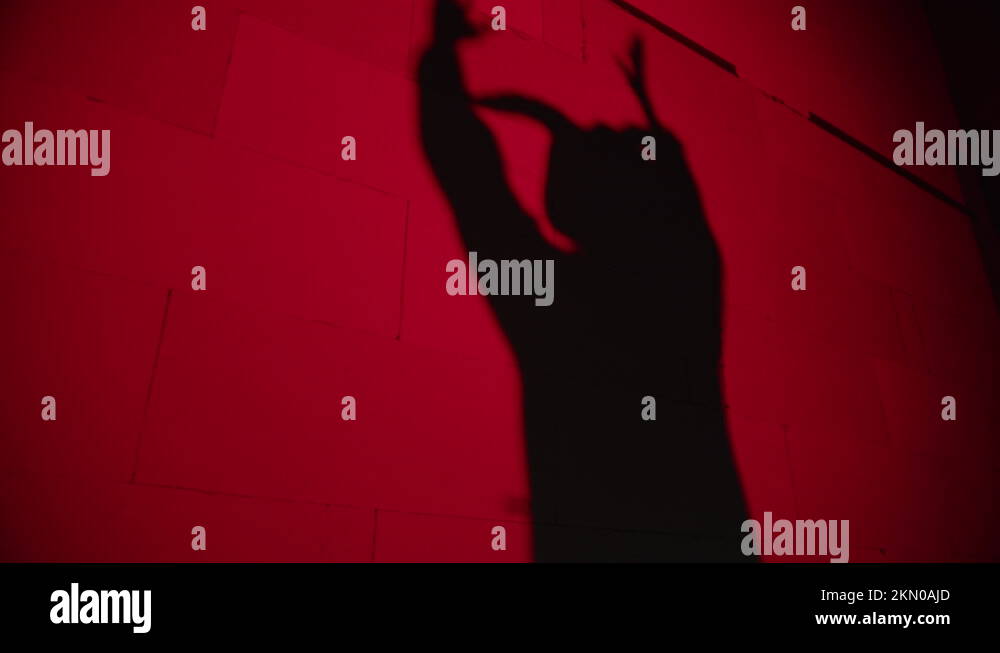 Demon with horns conjuring on red background close-up. Silhouette of ...