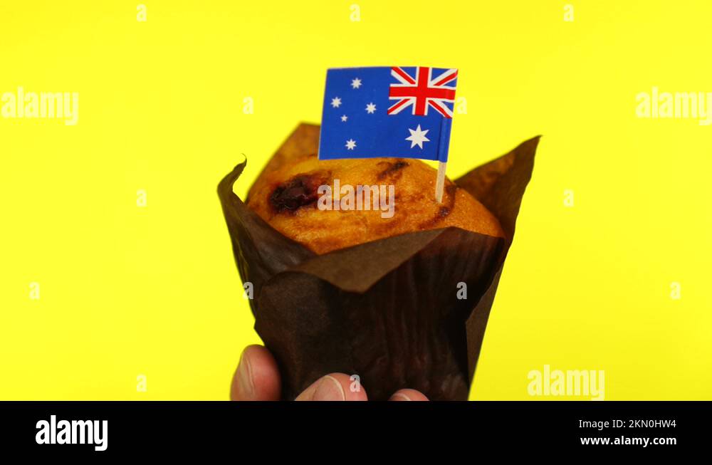 Cupcake with Australian flag on male palm against yellow background ...