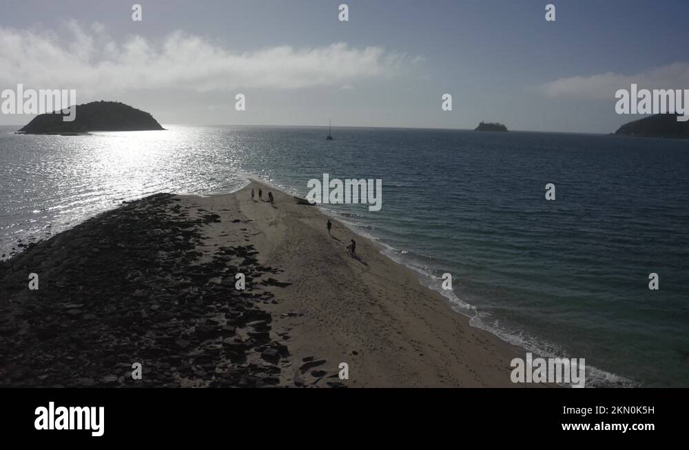 Inflatable boat on tiny beach spit with afternoon sun beam on ocean ...