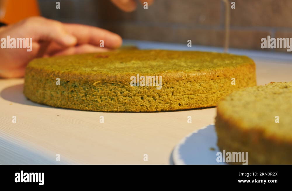 the baker saws off the spinach cakes from the biscuit with a special ...