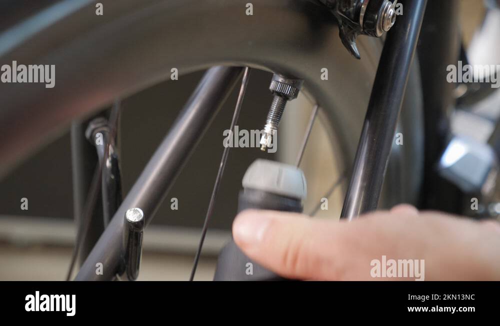 Bicycle mechanic pumping wheel in bike. Mechanic using hand pump to ...