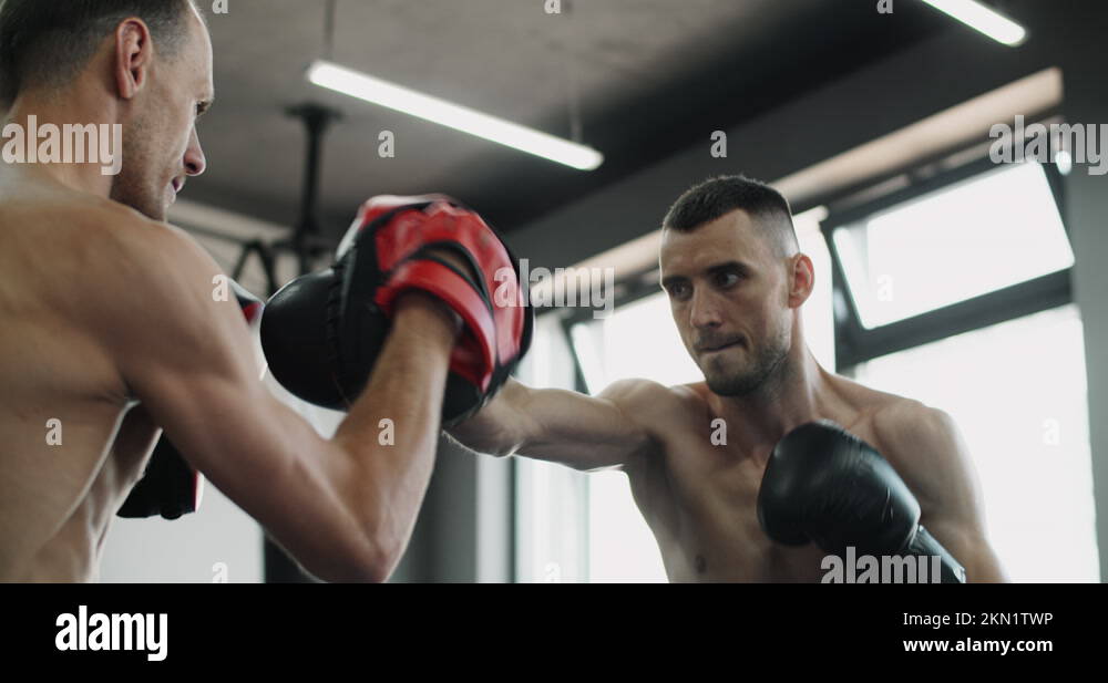 Low angle camera: fighter in boxer gloves is practising his strikes ...