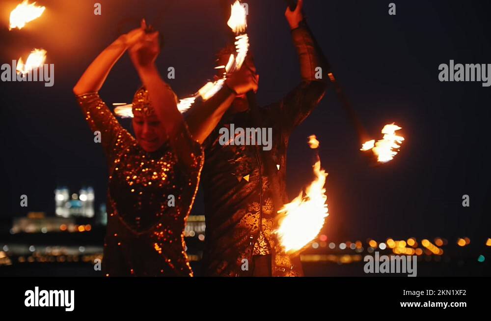 Fire show performance - man and woman in a shiny clothes playing with ...