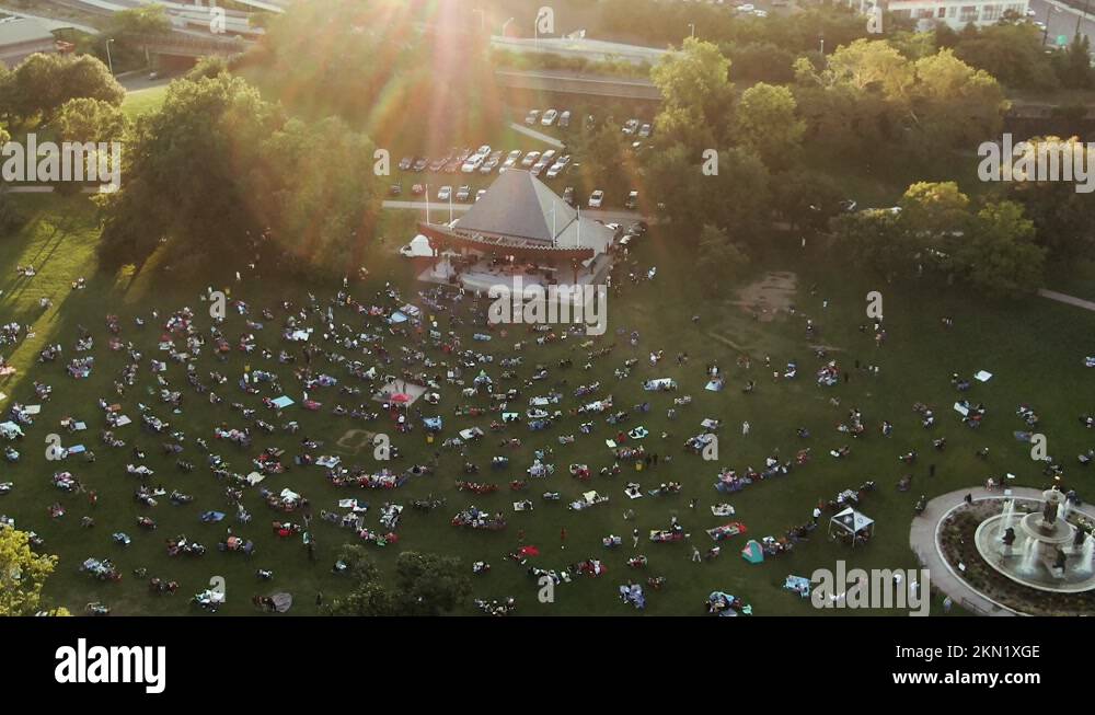Crowd of people sitting on grass field enjoying show on pavillion Stock ...