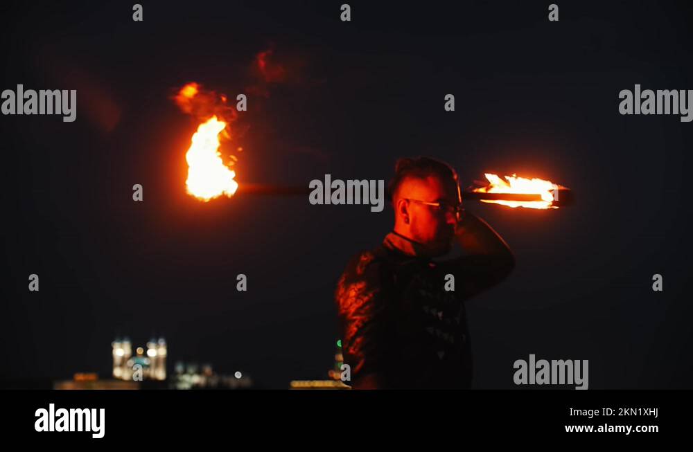 Fire show - a professional man dancing with a fire torch on the night ...