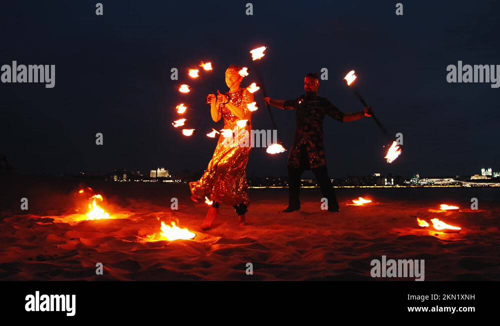 Fire show - woman and man performing dancing with torches on the beach ...