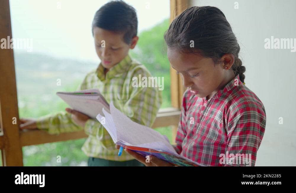 two little adorable primary school children holding books & reading in ...