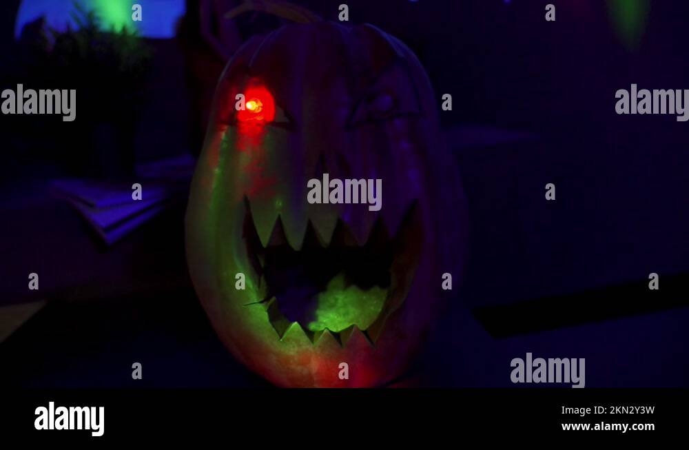 Scared pumpkin with an evil carved smiling grimace, glowing red and ...