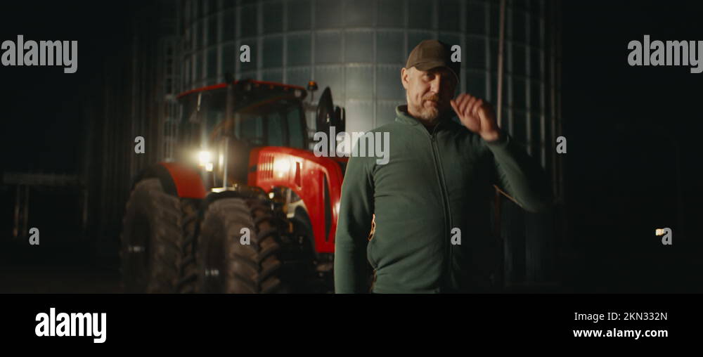 DOLLY IN Portrait of 50s farmer posing against tractor before sunrise ...