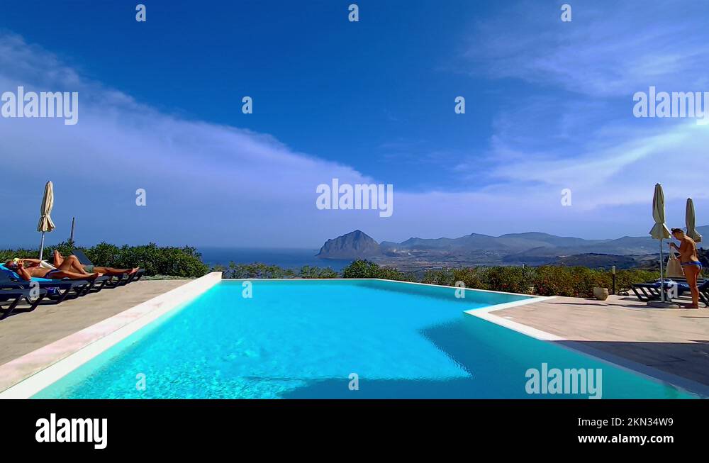 People sunbathing at luxury hotel with infinity pool overlooking ...