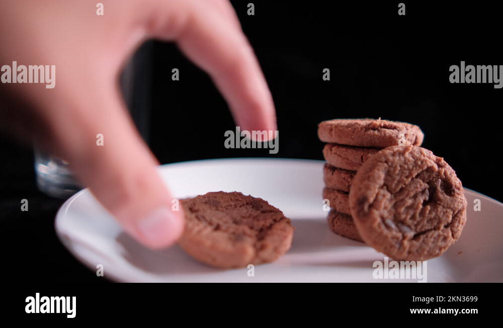 Hand grabbing cookie from a plate next to an empty glass Stock Video ...