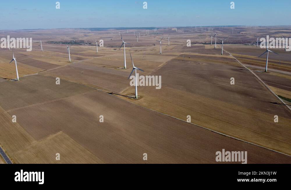 Rotating wind turbines on wind farm; drone ascending shot reveals open ...