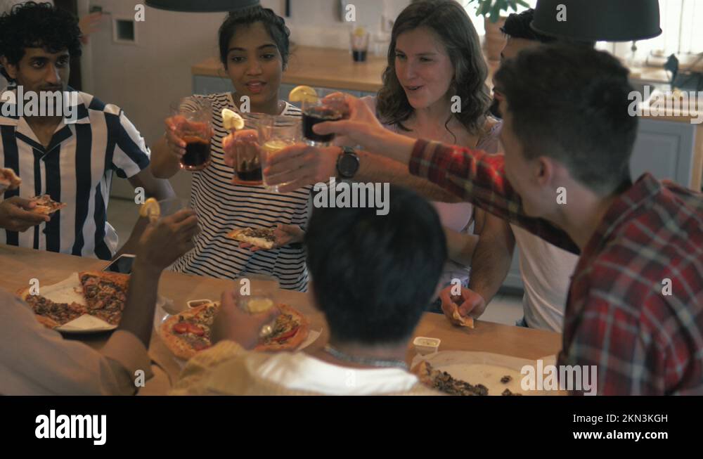 Multicultural diverse friends toasting, saying cheers eating pizza ...