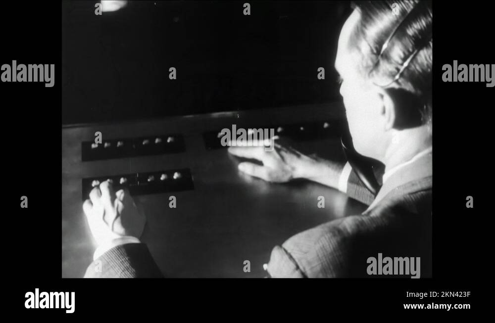 1950s: Orchestra playing on close-up screen. Control booth engineer ...