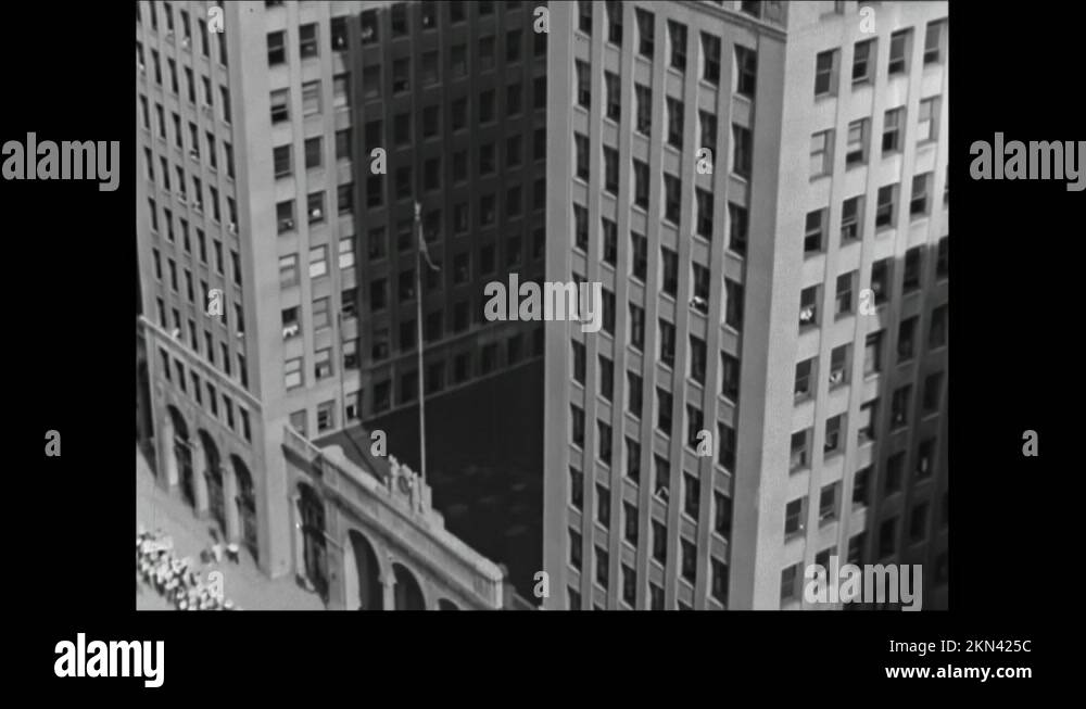 1940s: High angle of building, tilt down to people marching on sidewalk ...