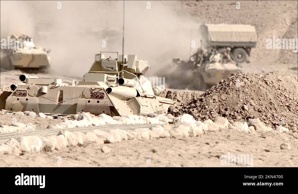 A column of armored vehicles with soldiers on armor drive past military ...