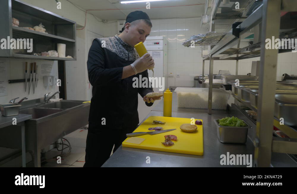 Young Fast Food Restaurant Cook Spreads Tasty Burger Sauce On Cut Bread ...