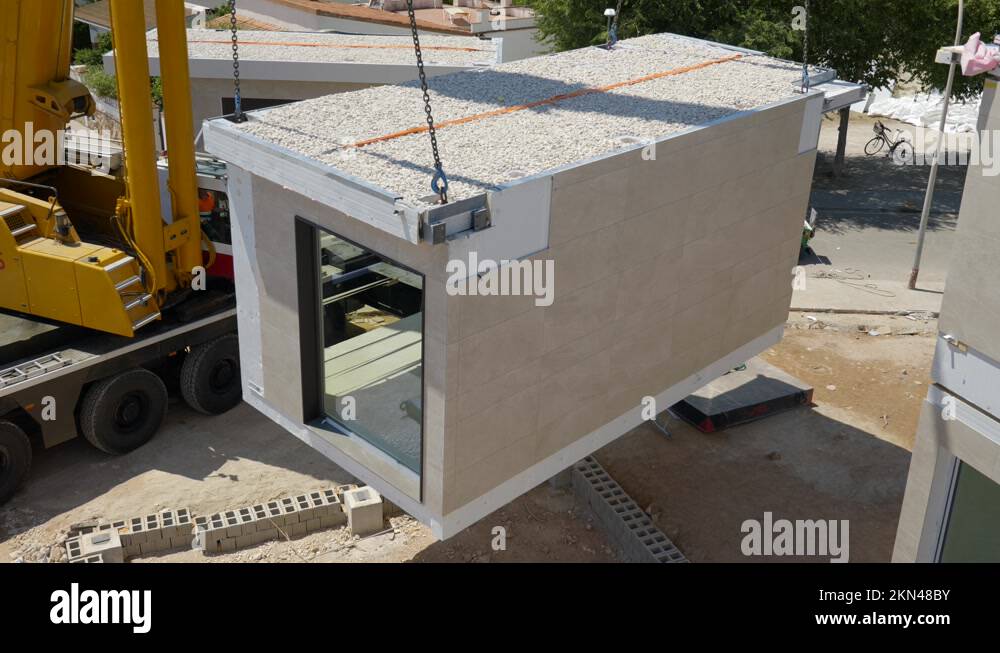Crane lifting simple modular housing onto real estate construction ...