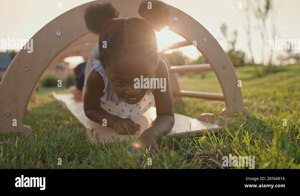 Two Girls Playing On Street On Roller Coaster. Black Girl Crawls Under ...