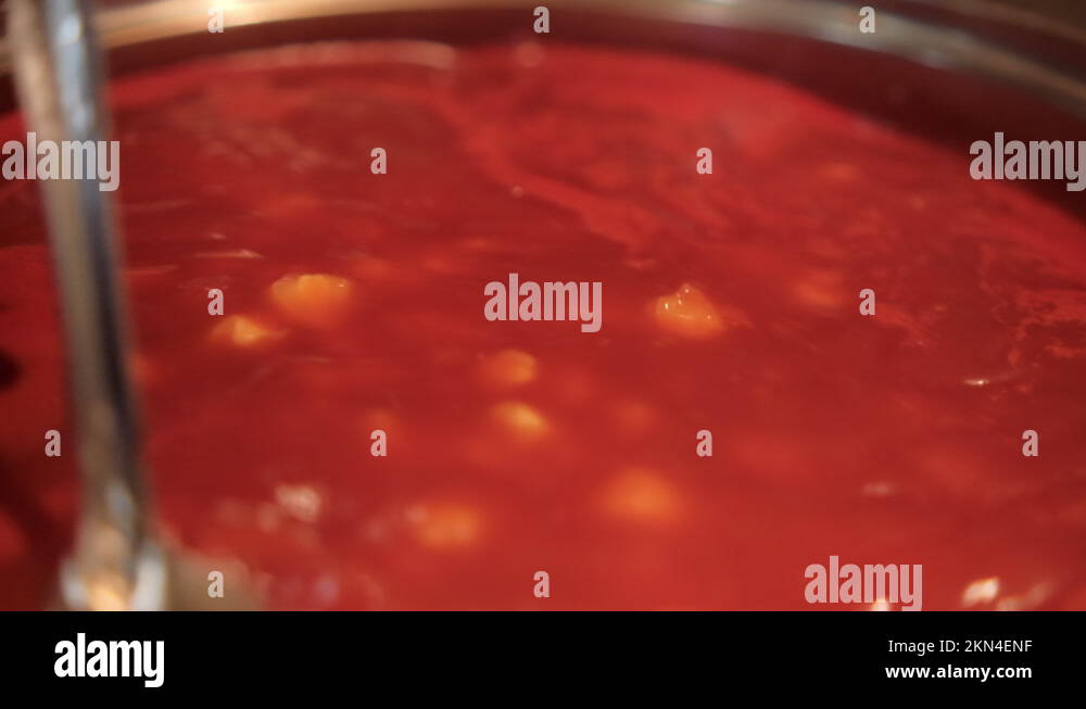 Spoon stirring delicious traditional Mexican pozole in cooking pot ...