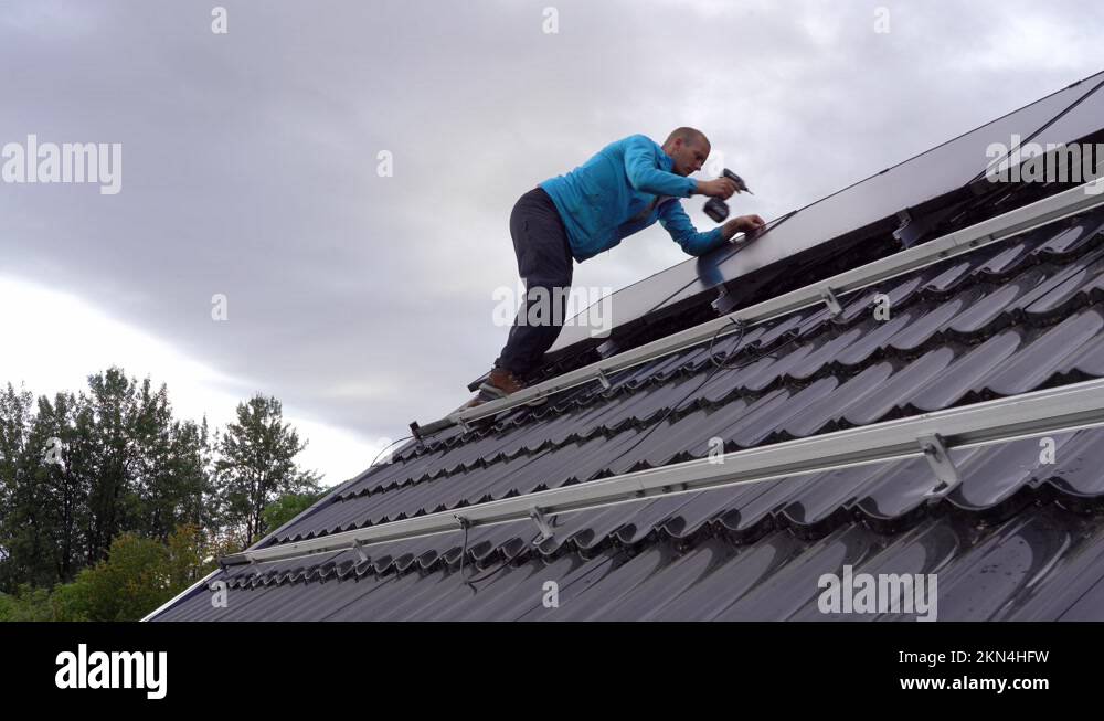 Male worker removing solar panels from roof - Removing brackets with ...
