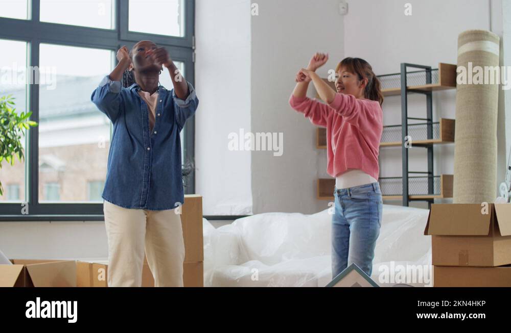 women with boxes moving in new home and dancing Stock Video Footage - Alamy