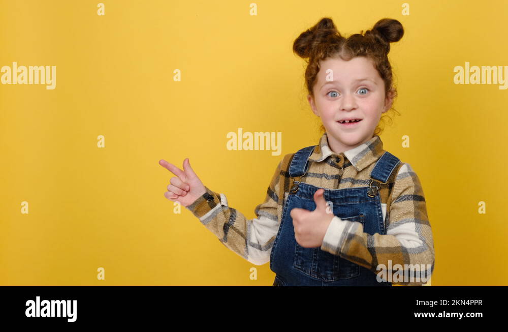 Cheerful little girl point index finger aside up showing thumb up like ...