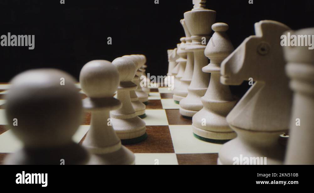 White chess pieces are lined up in even rows on a game board, ready for ...