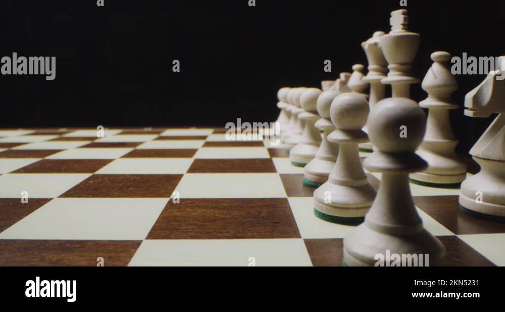 White chess pieces are lined up in even rows on a game board, ready for ...
