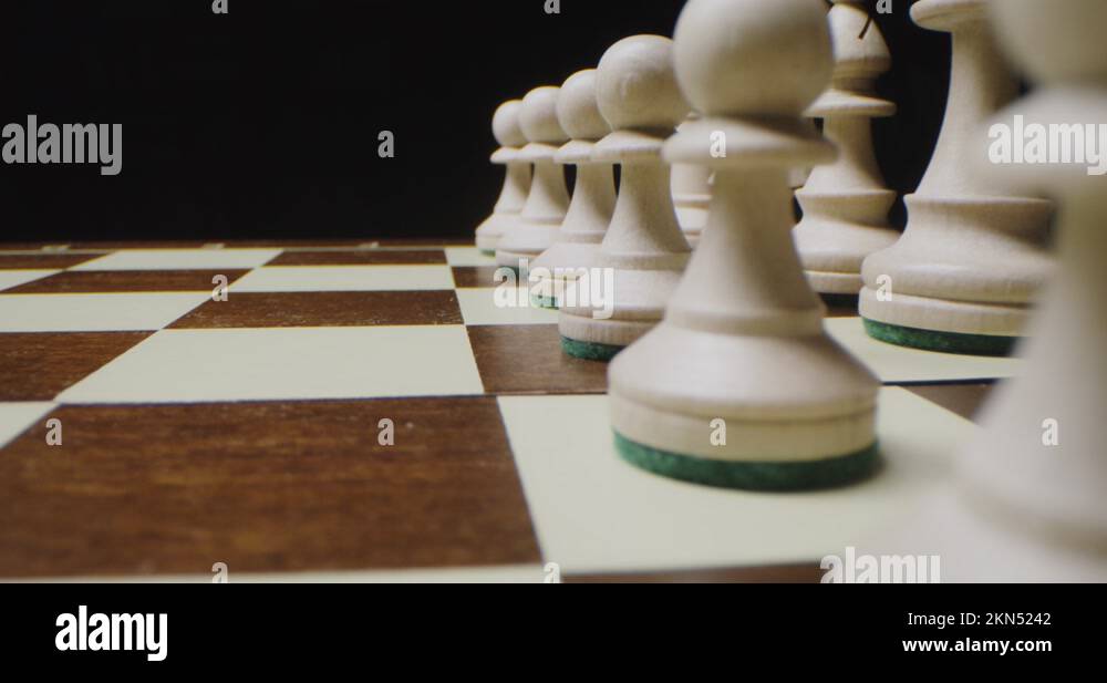 White chess pieces are lined up in even rows on a game board, ready for ...