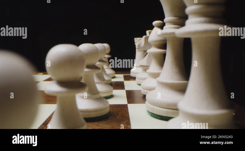 White chess pieces are lined up in even rows on a game board, ready for ...