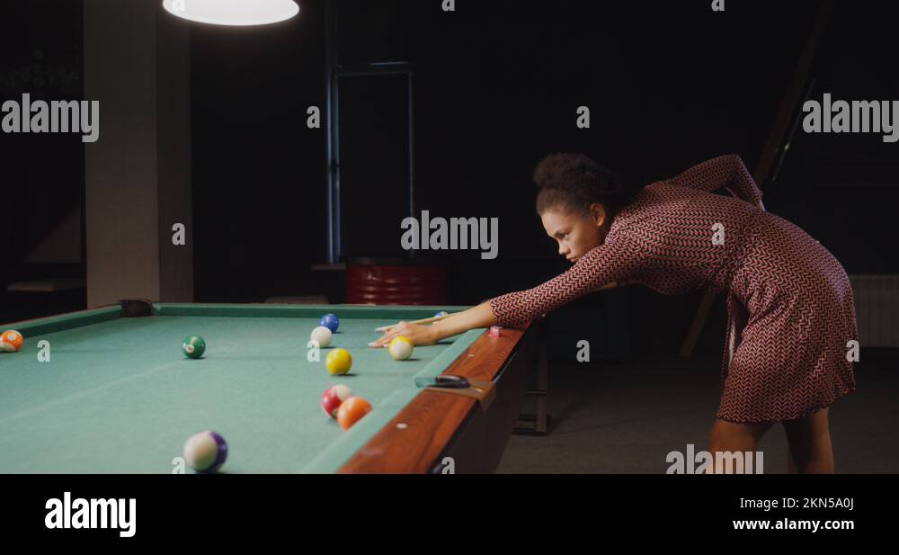 Beautiful young african american woman plays billiards alonein a ...