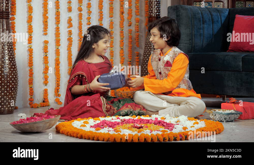 Brother in traditional wear giving a colorful gift to his cute little ...