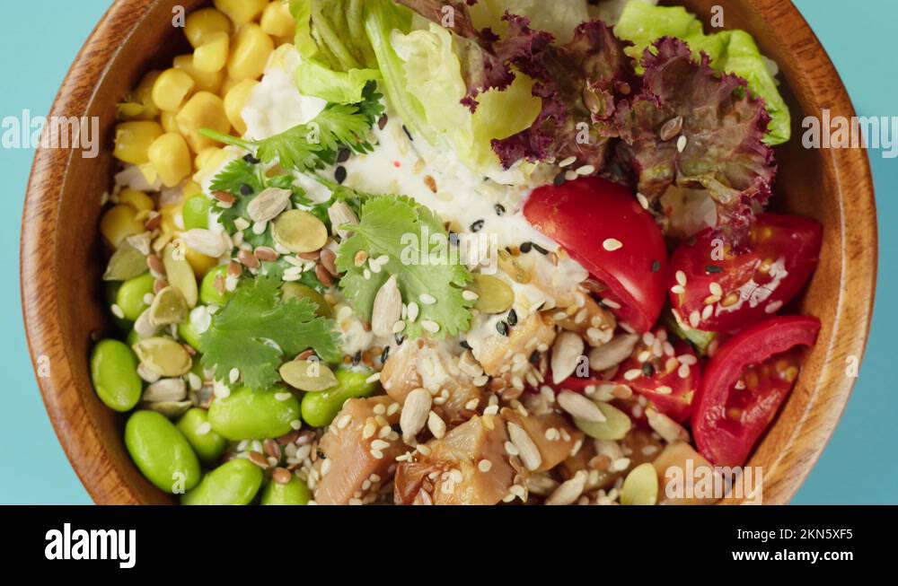Poke bowl salad on blue background. Sliced vegetables, fried meat ...