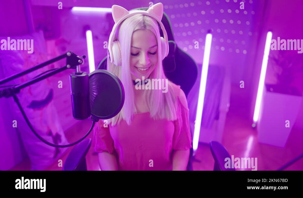 Cute gamer girl streamer typing and talking to fans from her pink room ...