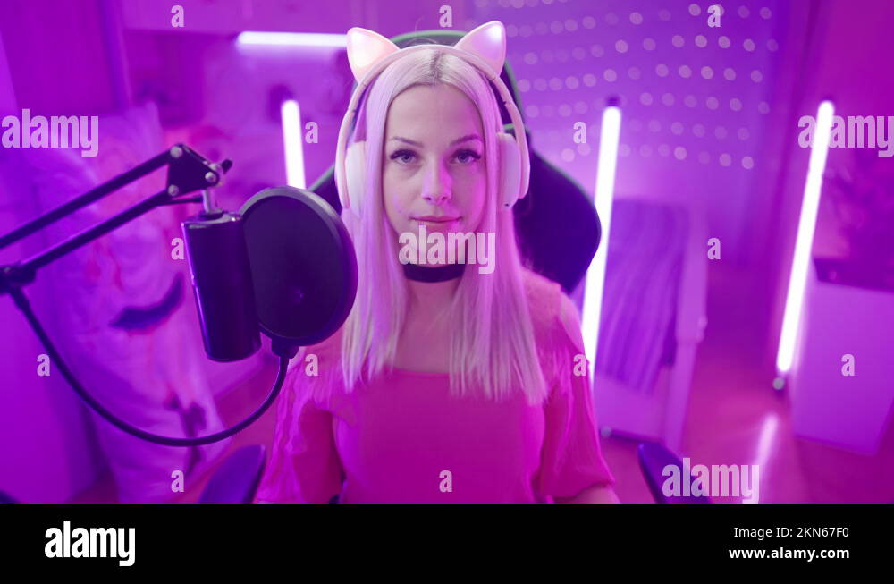 Blonde Gamer Girl wearing cat ear headphones in pink room stare in ...