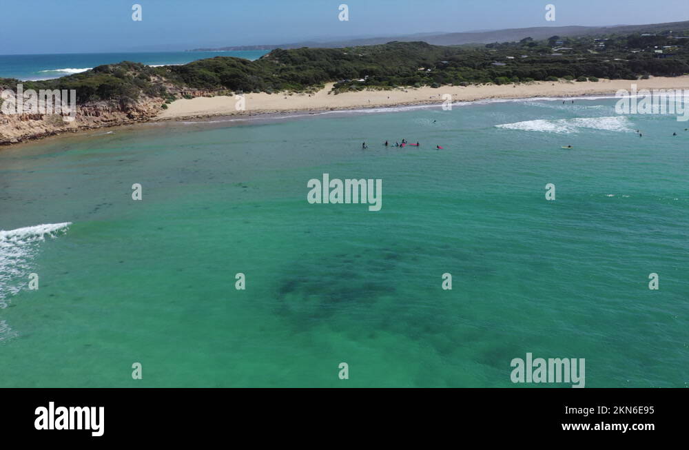 Rotating aerial of group of kids learning to surf in protected bay ...