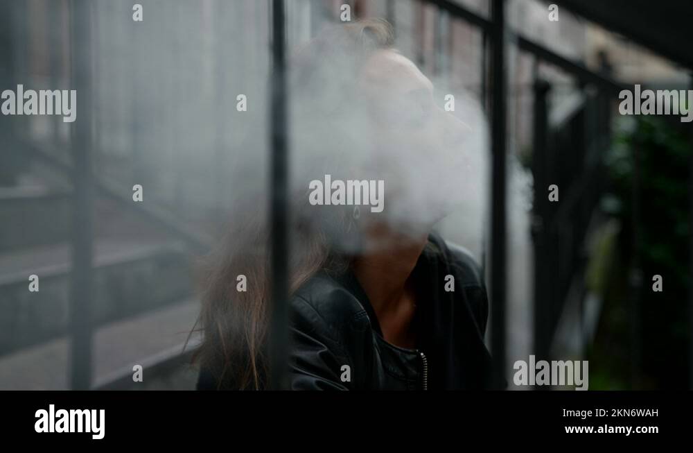single lady is smoking cigarette, sitting on stair of old house in town ...