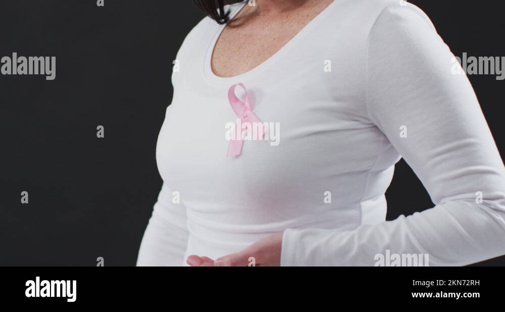 Mid section of a woman showing the pink ribbon on her chest against ...
