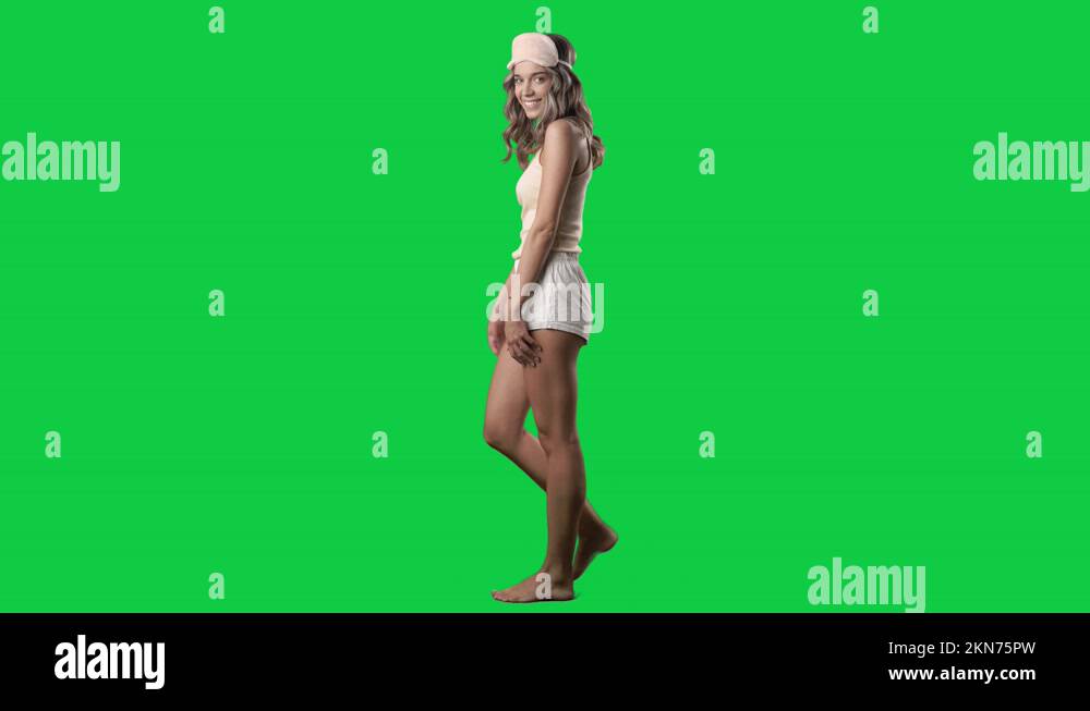 Side view of woman in sleepwear walking and waving. Full body on green ...