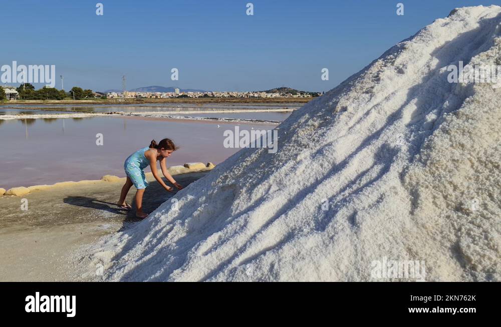 Little redhead girl playing with salt and eat it atSaline of Paceco ...