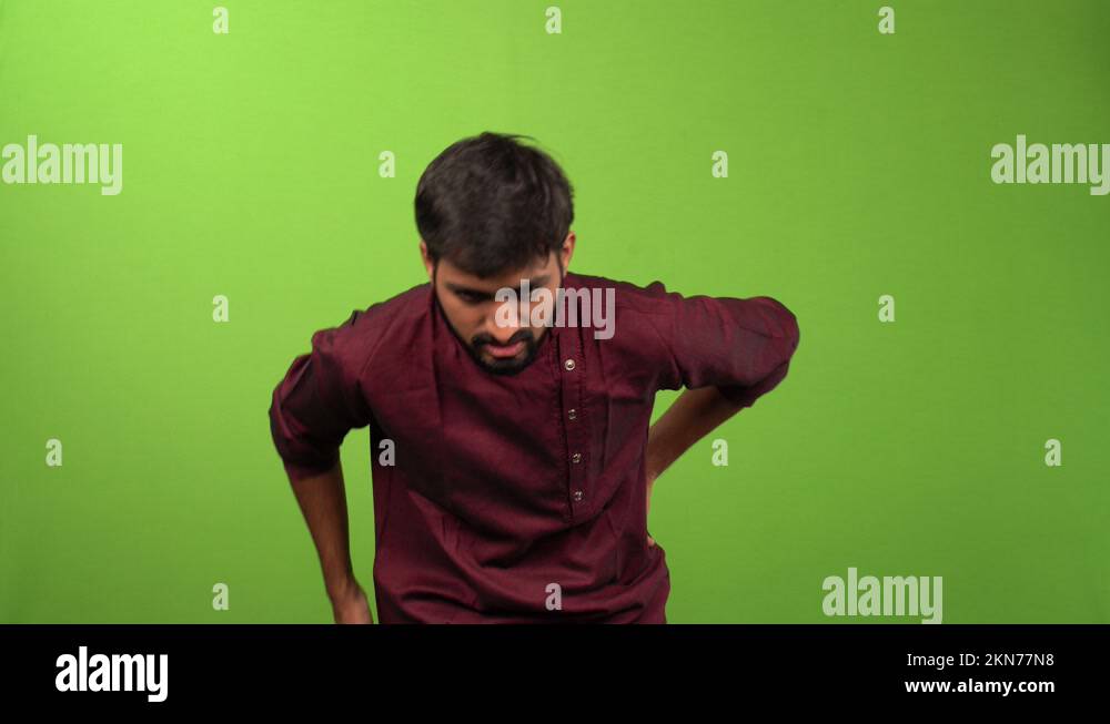 Indian man writhing in back pain with hands on his back and moving side ...