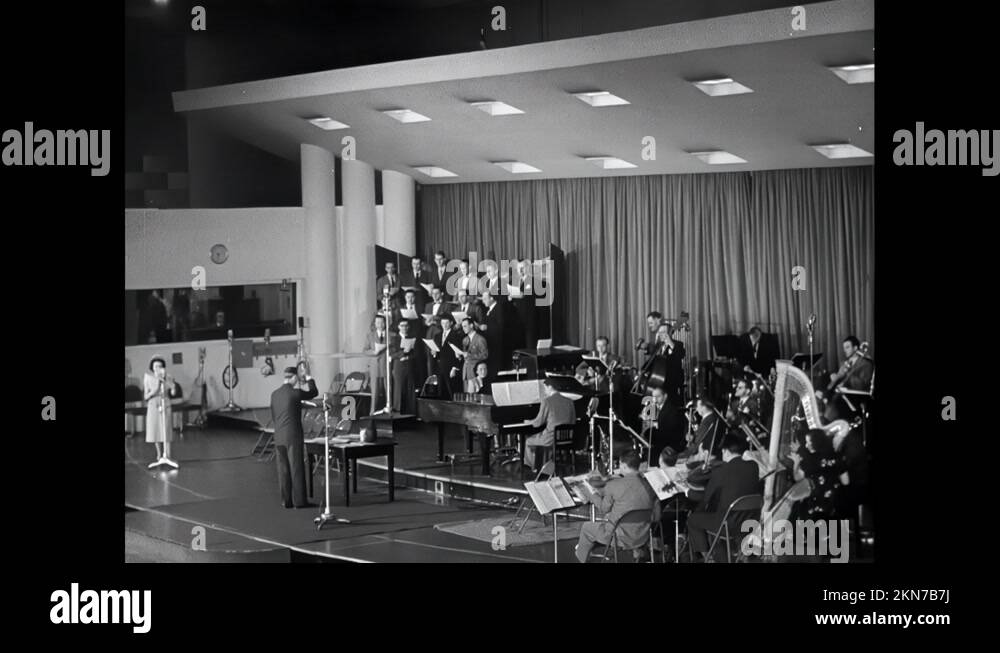 1940s: Man conducts musicians and singers in soundstage. Men in control ...