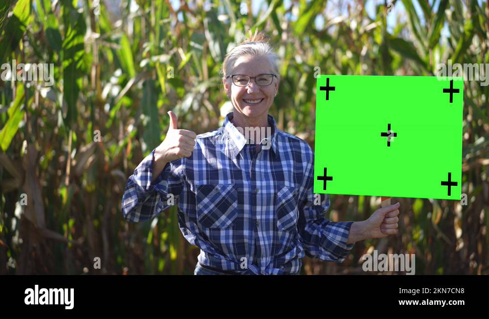 Happy, smiling farmer woman holding green screen chroma key sign in ...
