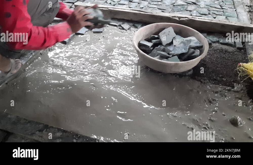 skilled builders put crazy Crazy paving ceramic tiles on the wet ...