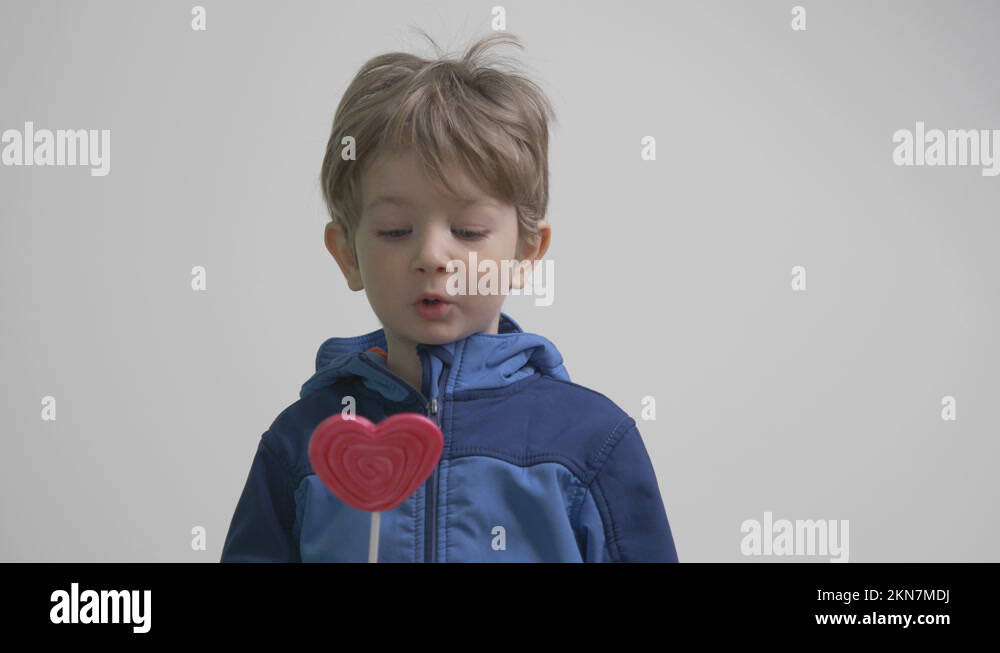 Pretty kid licking his lips while looking at big red heart-shaped ...