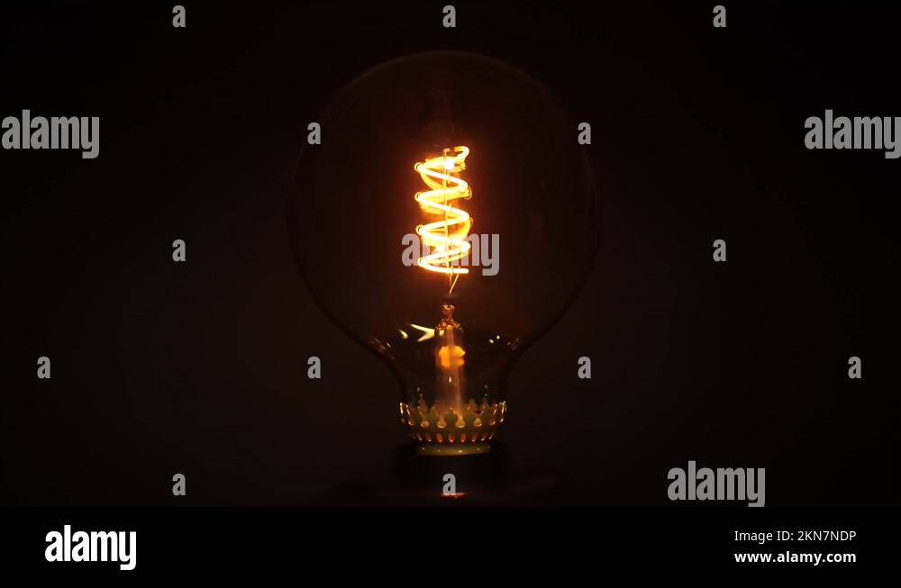 Light bulb flickering over dark black background. Tungsten bulb ...